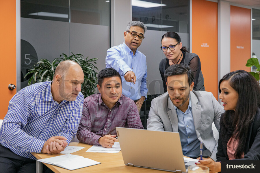 Working together in an office space by Tobias Kraus - Truestock